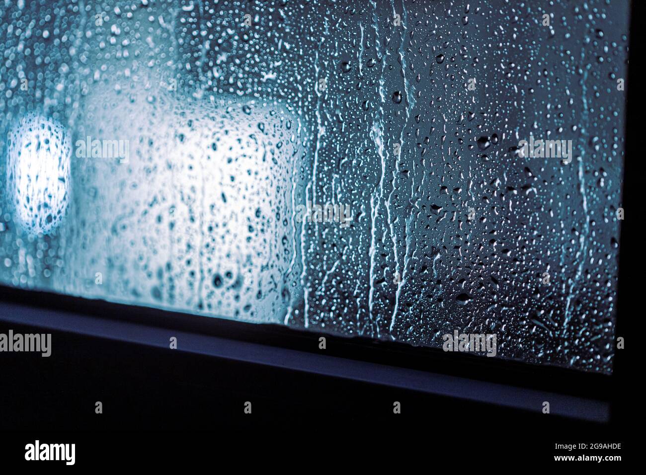 Close up of rain drops on the window in rainy night, cool lights and ...