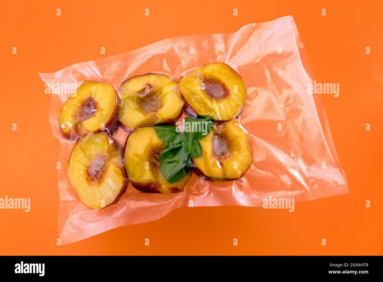 Peaches cut in half with mint leaves in vacuum packed sealed for sous ...