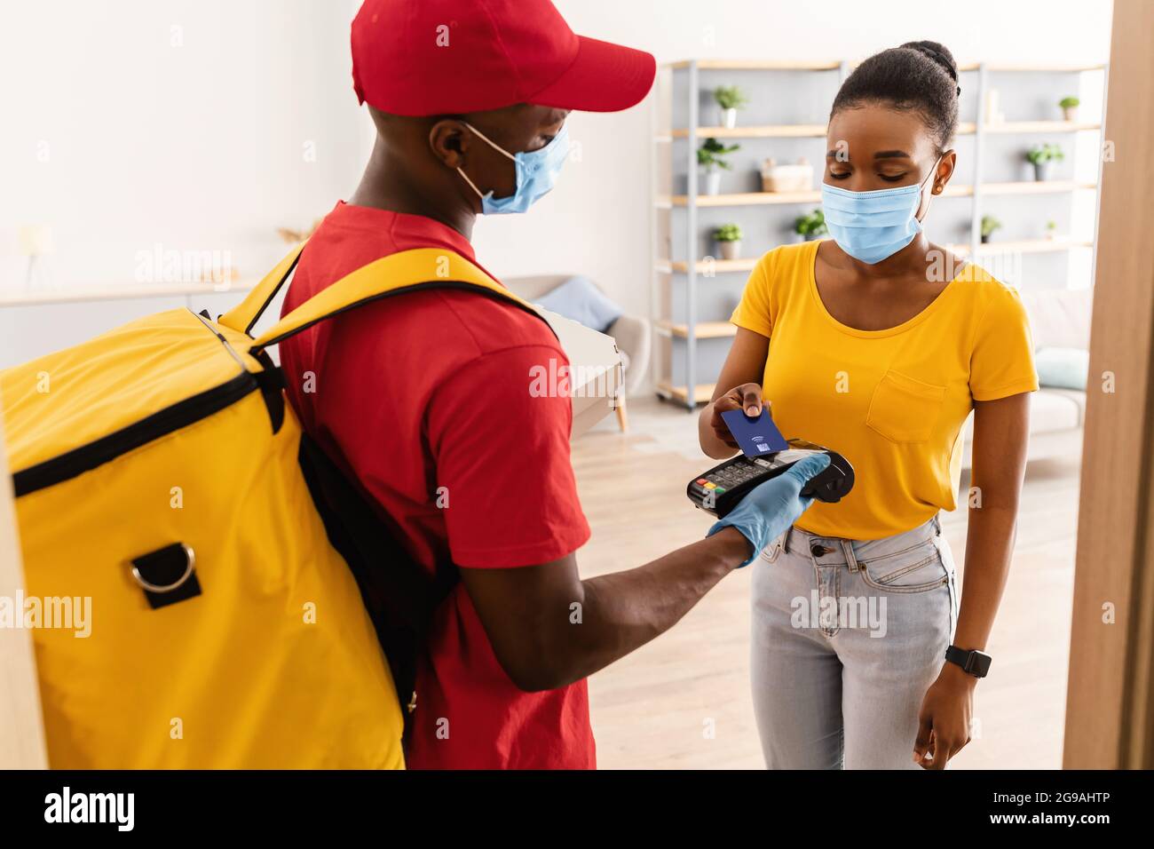 Courier Holding Terminal While Female Paying With Credit Card Indoors ...
