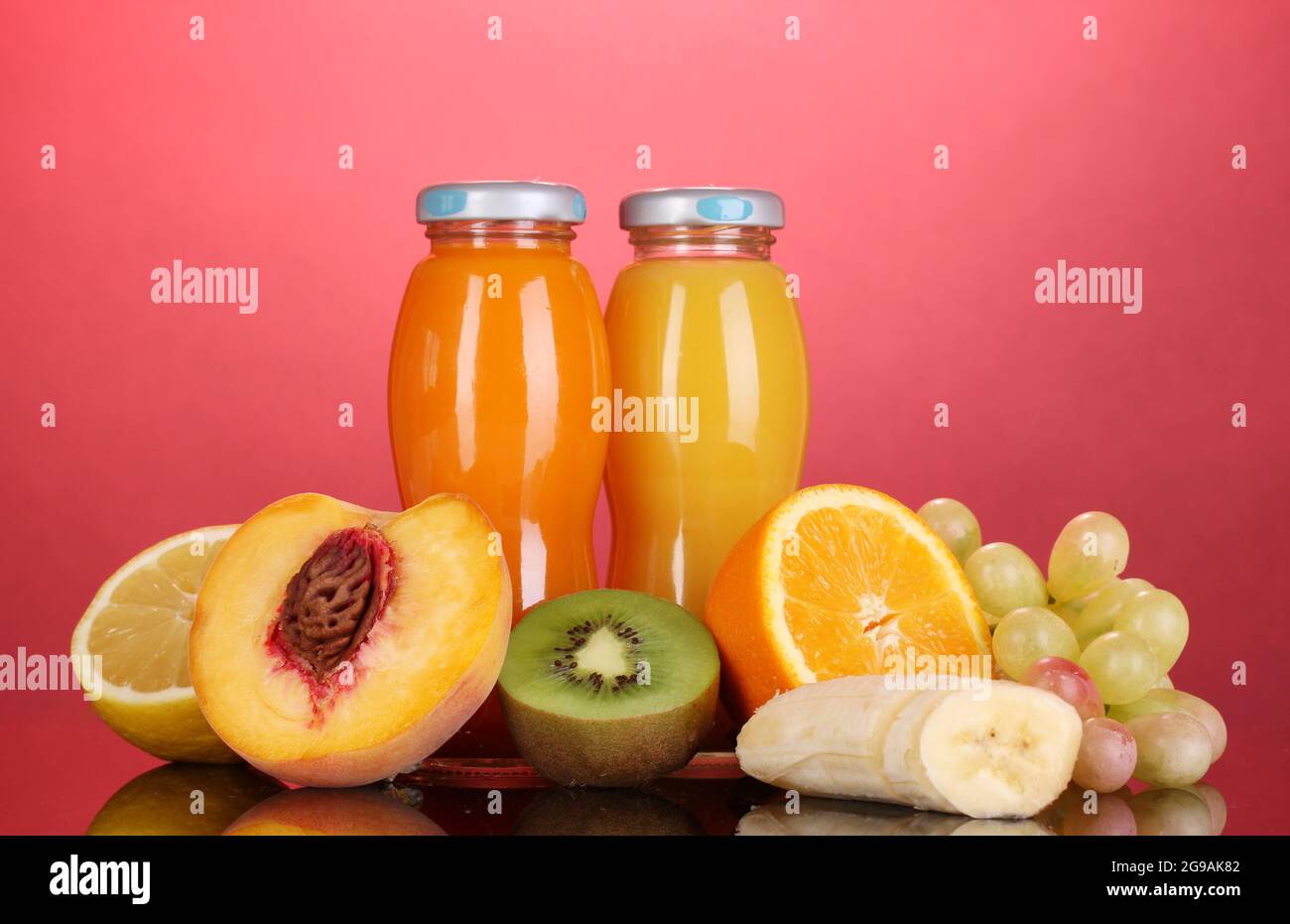 Delicious multifruit juice in a bottle and fruit next to it on pink ...