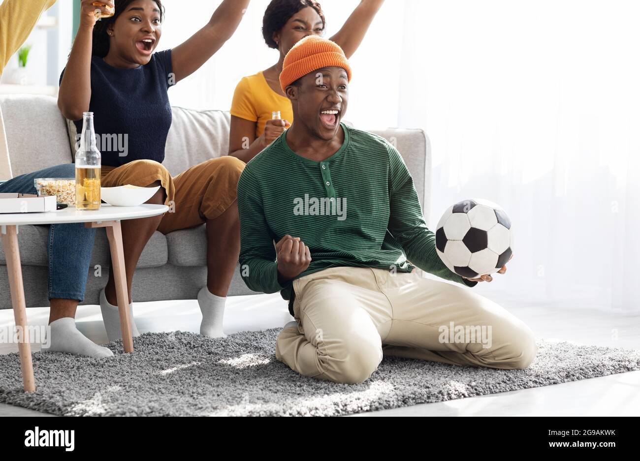 Ecstatic football fans watching game together at home, copy space Stock ...