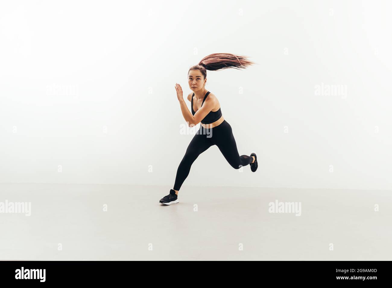 Front view of muscular woman running in studio against white wall Stock ...
