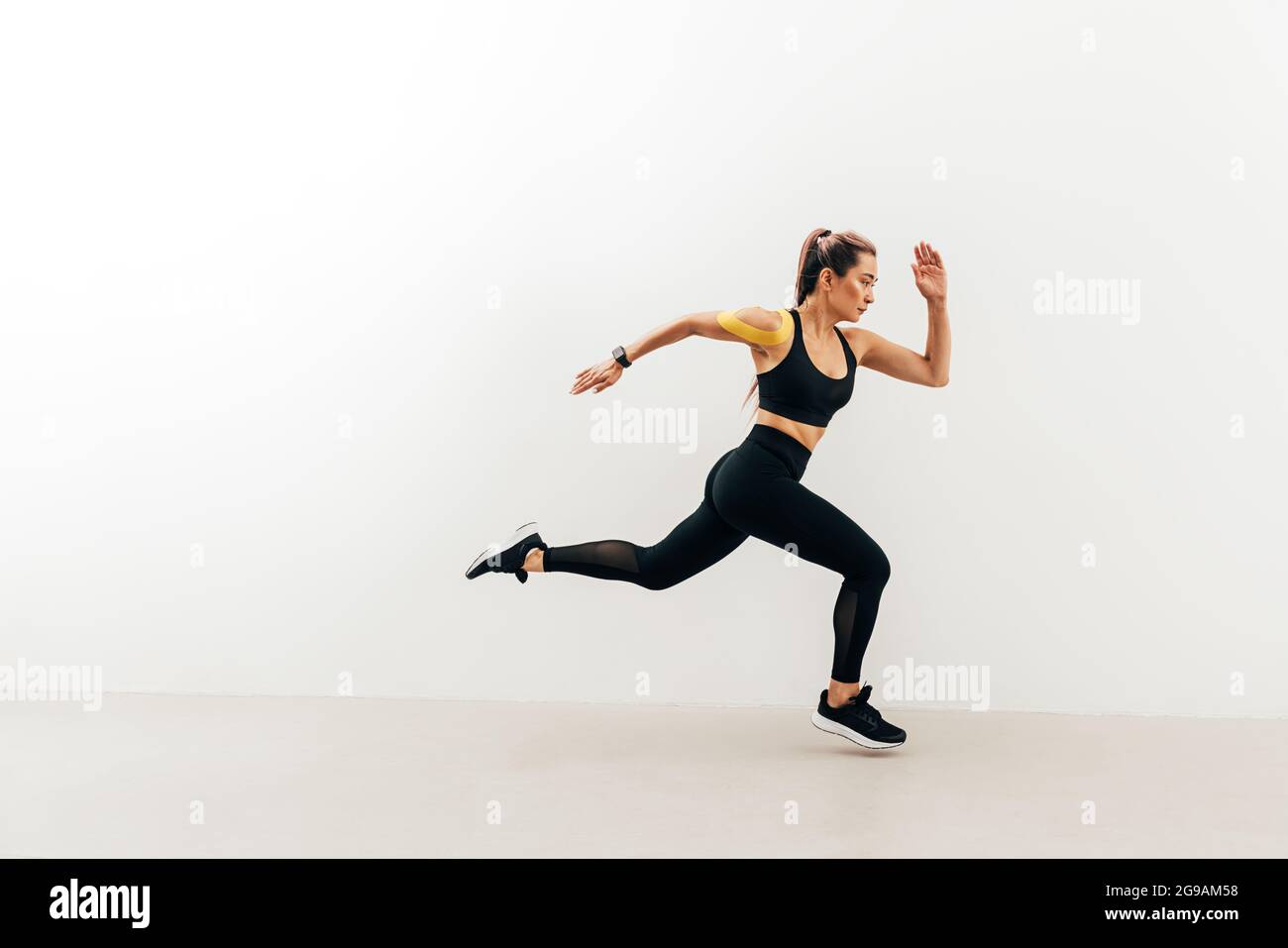 Side view of female athlete sprinting near a white wall Stock Photo - Alamy
