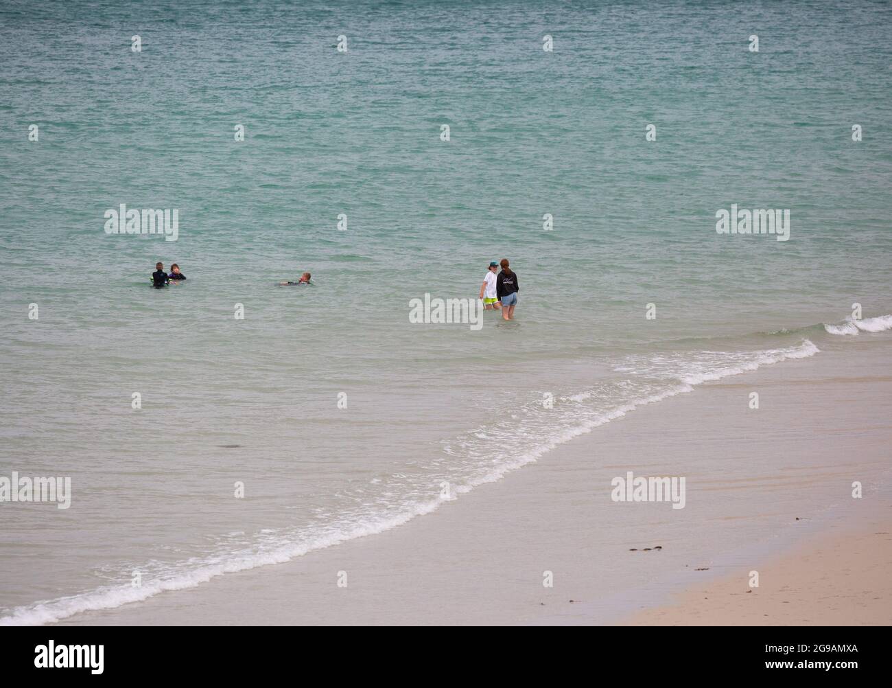 People on the beach by the turqoise sea in Sennen Cove, cornwall, uk ...