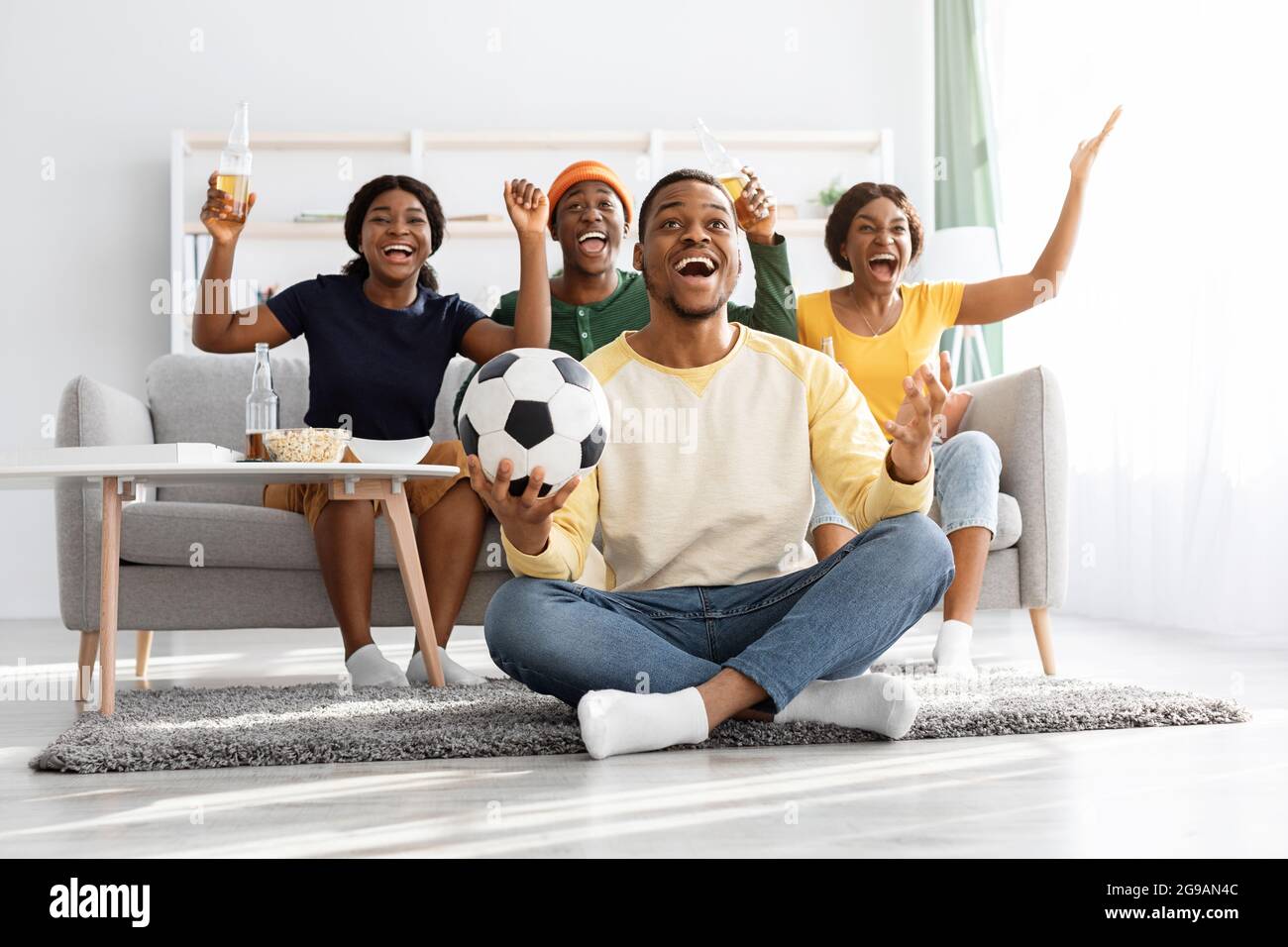 Emotional football fans watching game together at home, celebrating win ...