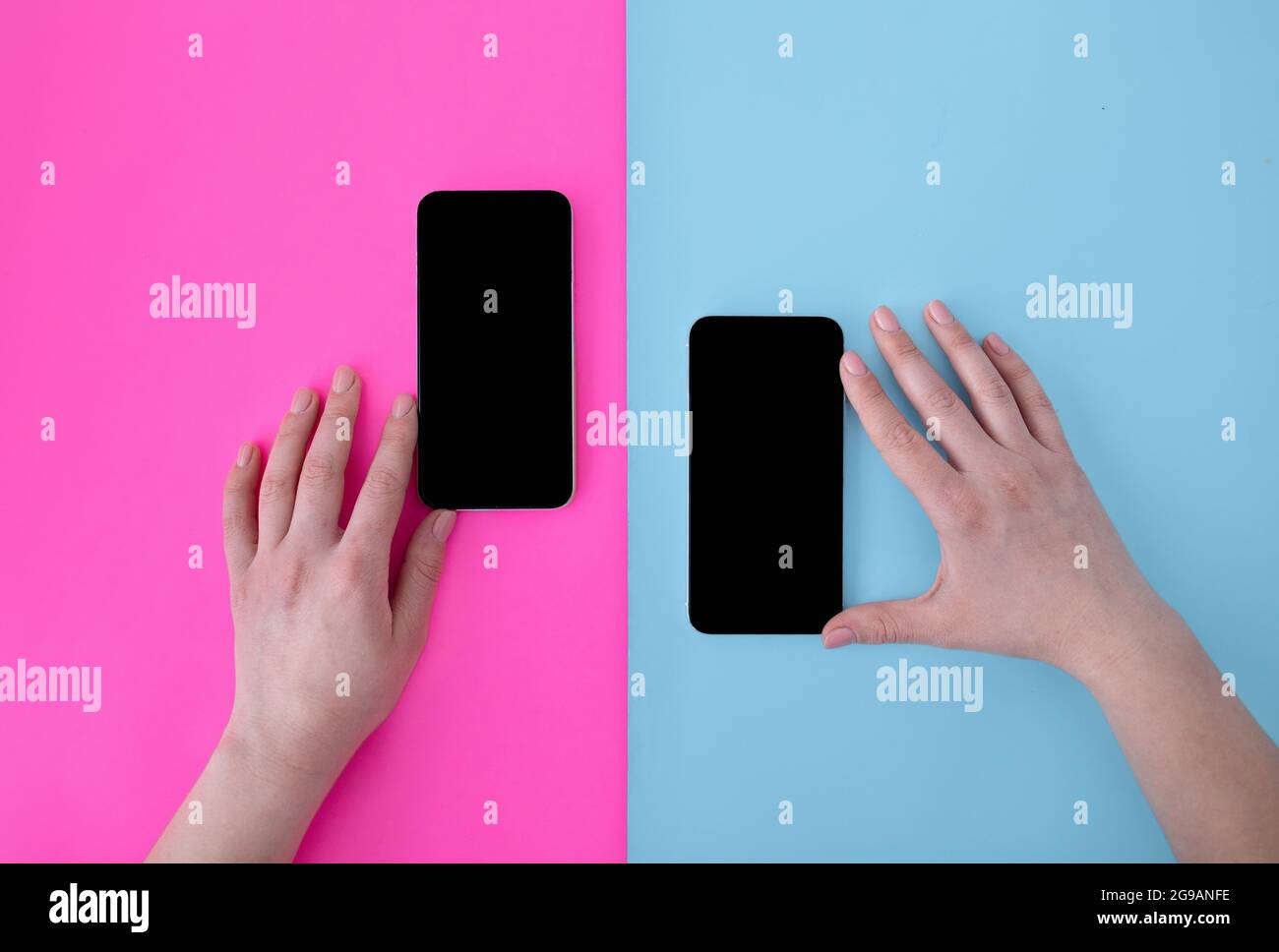 Female hands touching two smartphones with blank screens on blue and ...