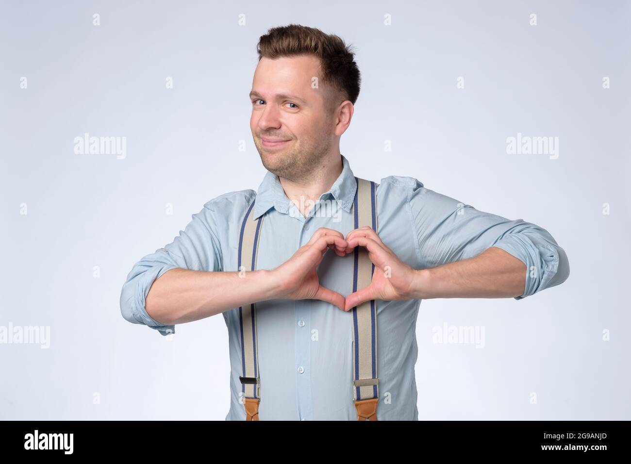 Smiling young man making heart gesture on his chest Stock Photo - Alamy