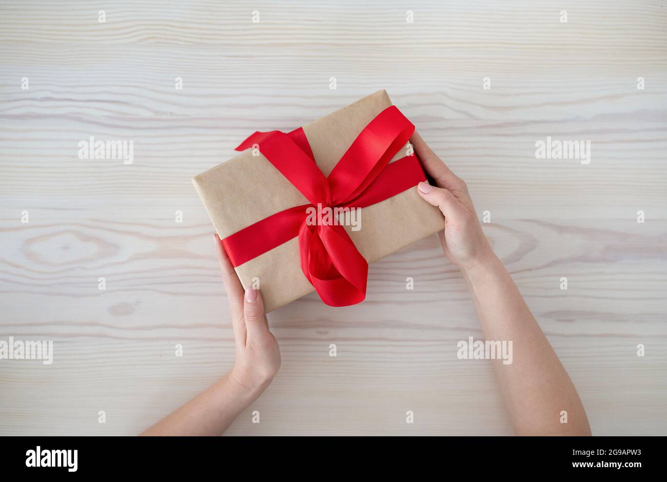 Present decoration. Female hands holding wrapped holiday handmade gift ...