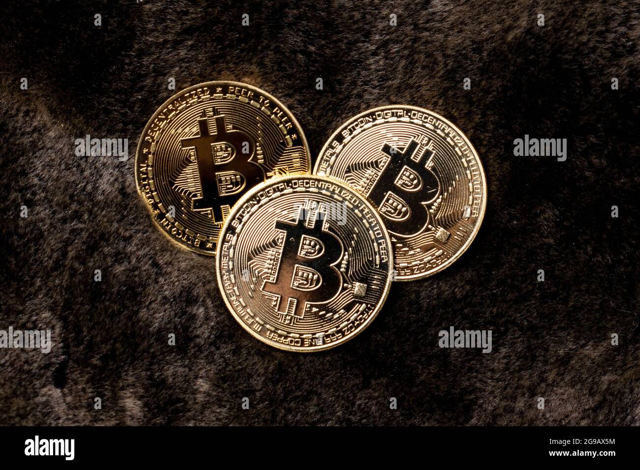 Three bitcoin coins of gold color on a background of dark fur Stock ...