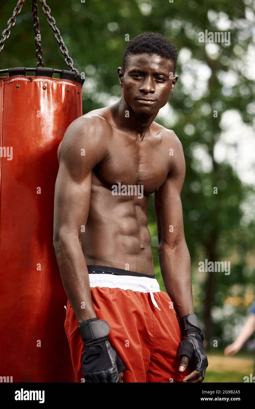 Muscular black professional boxer sweating in gloves boxing training ...