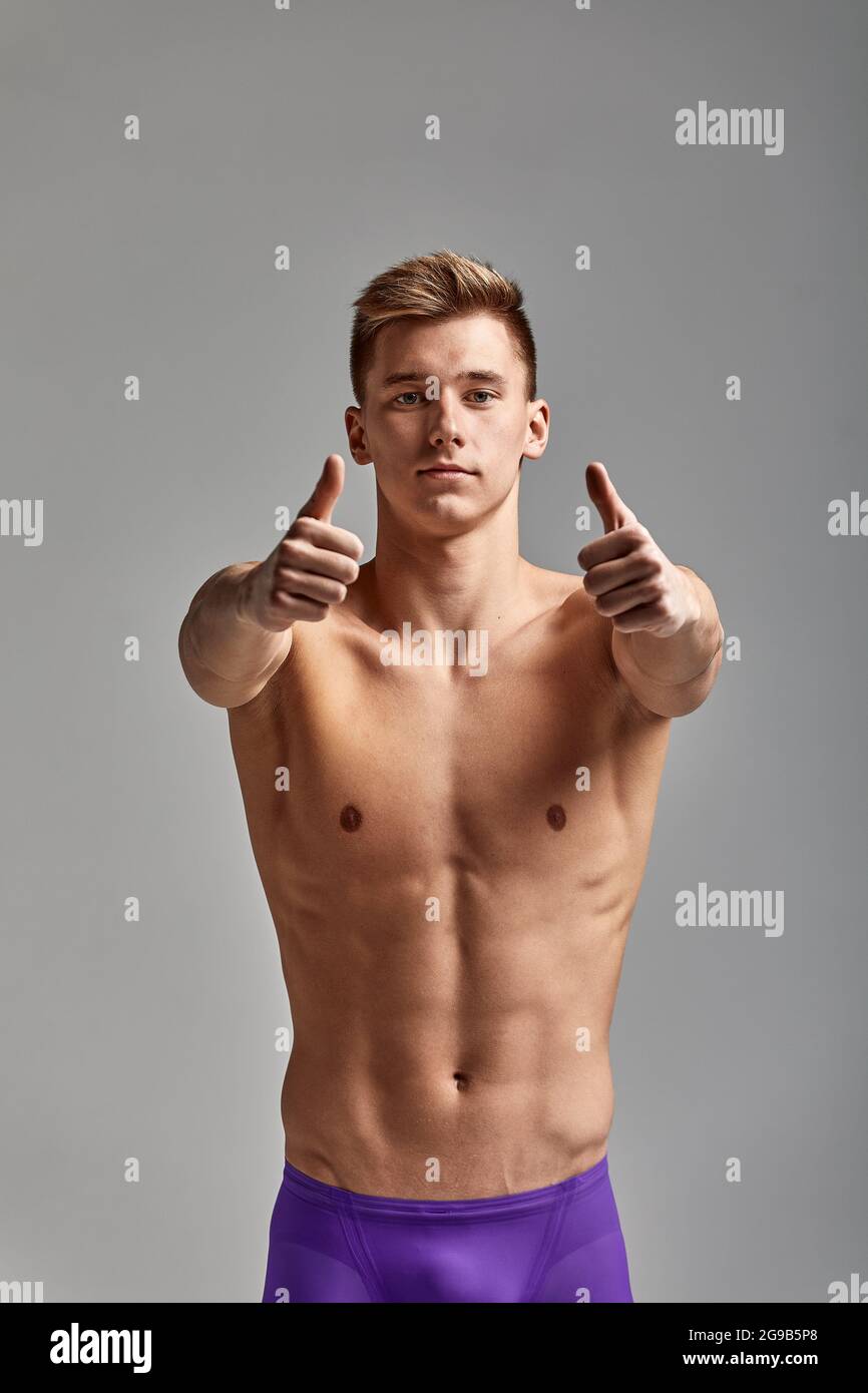 Handsome fit man holding thumbs up, showing great shape, sportsman ...