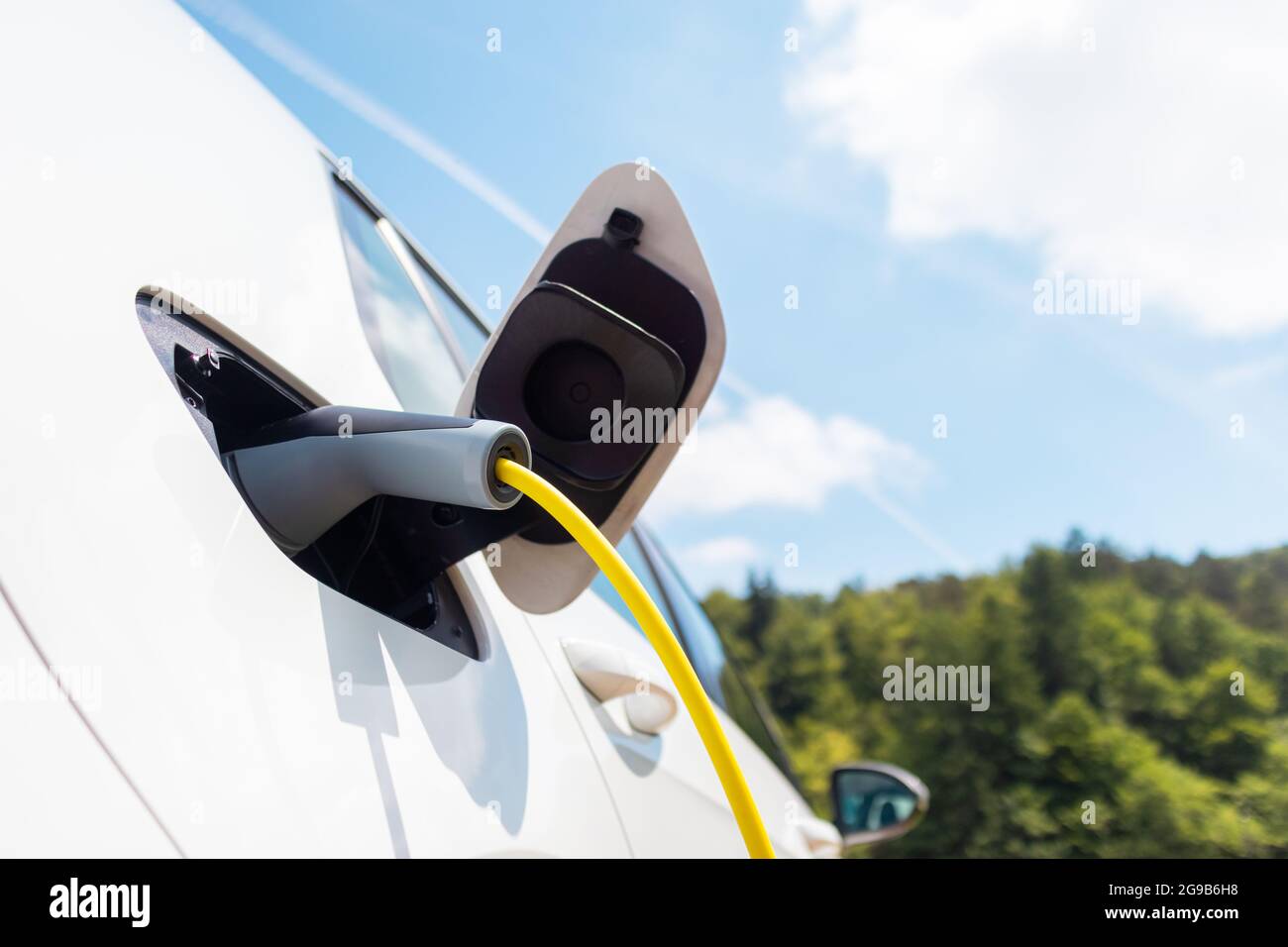 Electric car charger plugged in at home backyard Stock Photo - Alamy