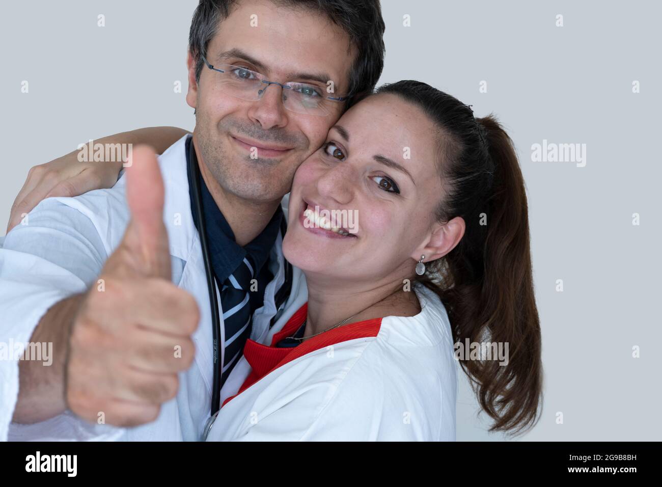 Doctor and nurse hug each other smiling and show thumbs up ...