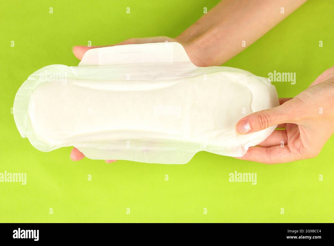 woman's hands holding a sanitary pad on green background close-up Stock ...