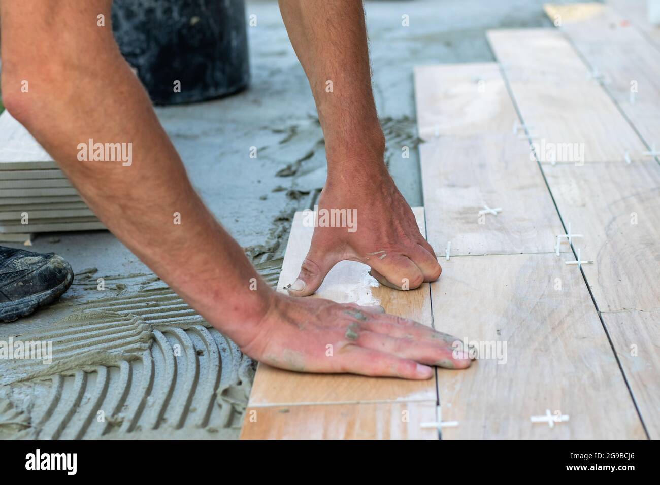 The hands of the professional tiler lying or installing modern, ceramic ...
