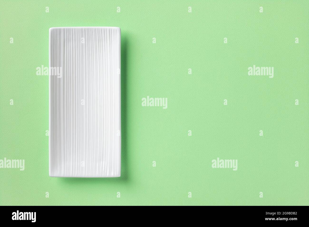 White rectangular ceramic plate over mint green textured background ...
