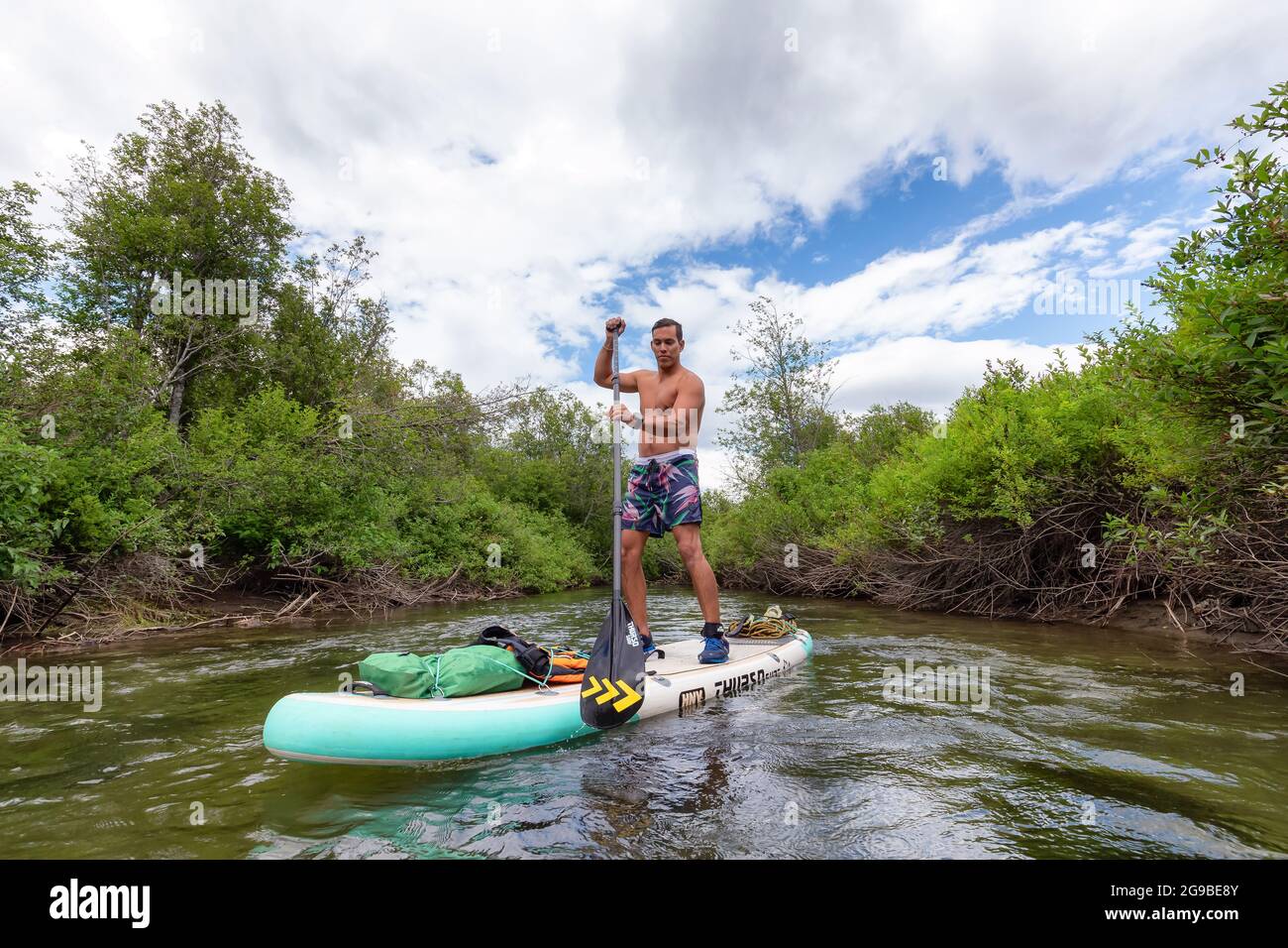 Adventurous people paddle boarding in a river Stock Photo - Alamy