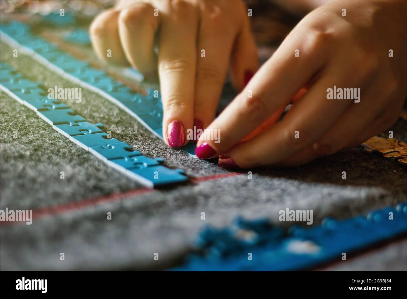 Hand of a woman with nail polish playing Jigsaw Puzzle, starting to ...