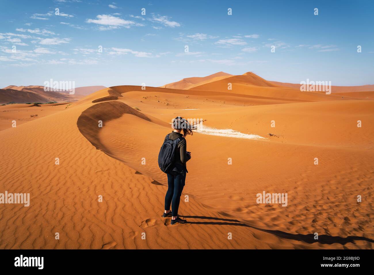 Active female traveler hiking on the dunes around Deadvlei in the Namib ...