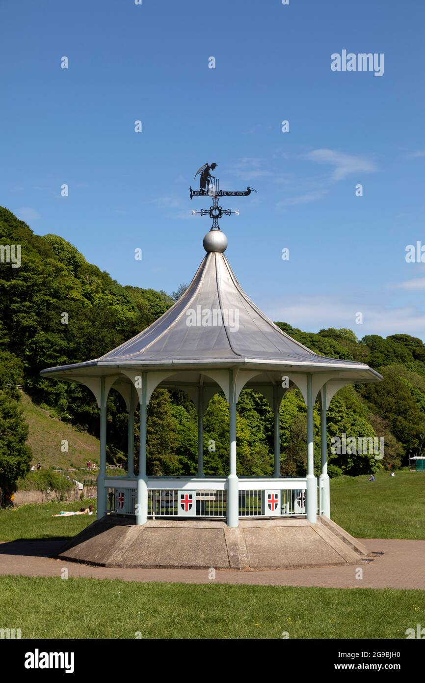 Riverside bandstand with a weathervane bearing the words, "Lest time ...