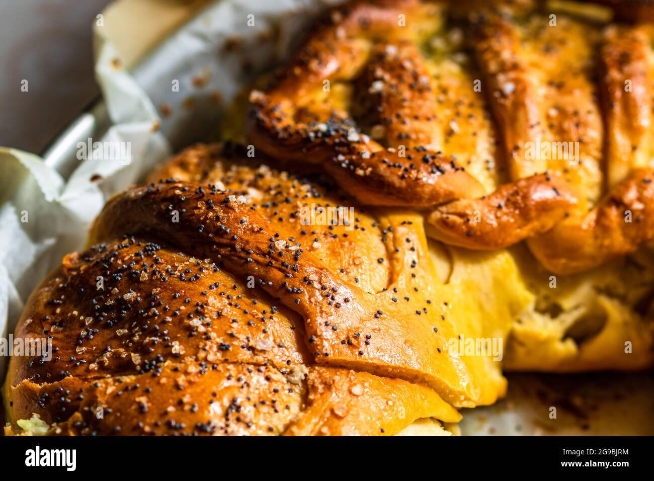 An overhead shot of salt and poppy seeds over a braided puff pastry ...