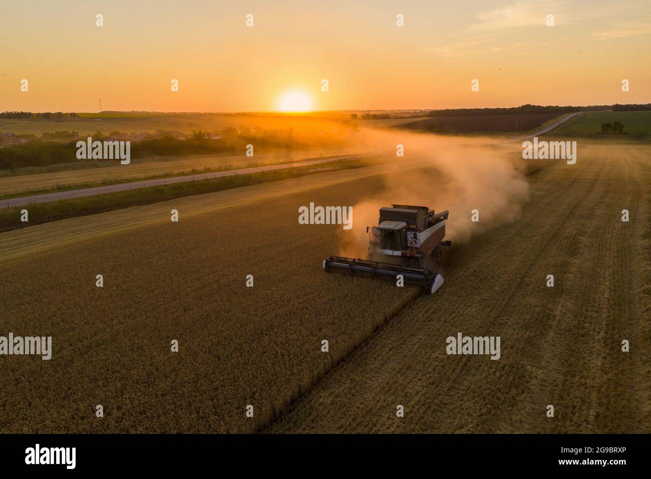 Combine harvester on the field at sunset. Aerial view Stock Photo - Alamy