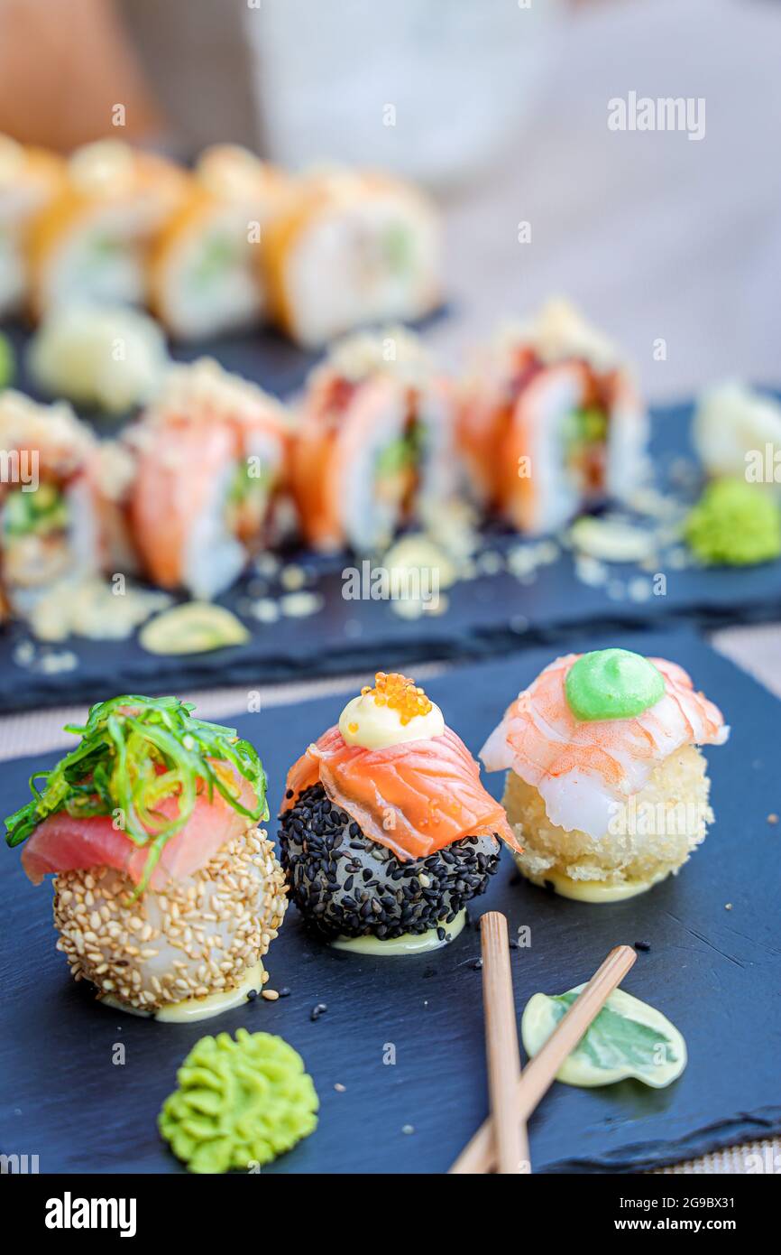 A vertical shot of assorted sushi delicious rolls on a black wooden ...