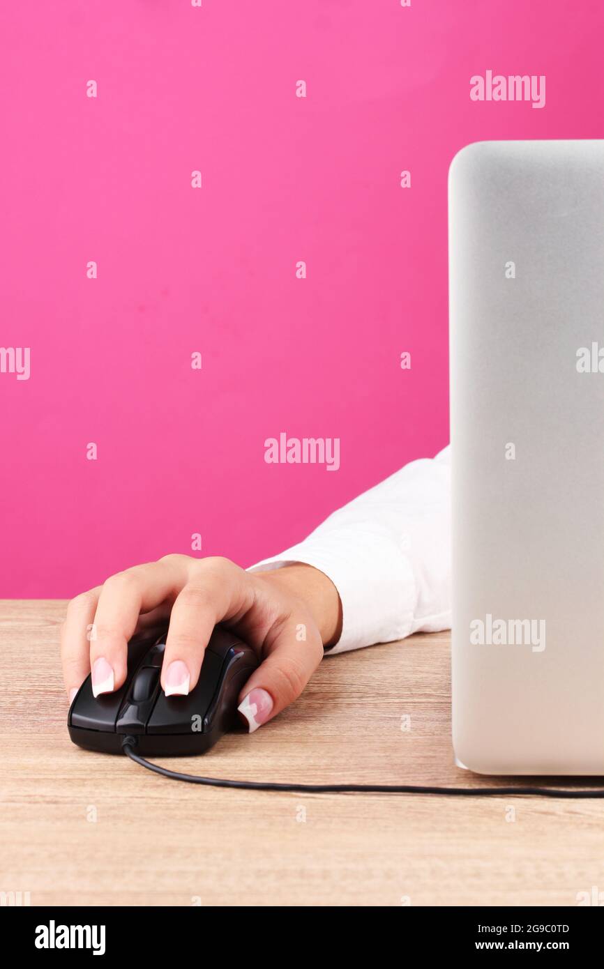 woman's hands pushing keys of pc mouse, on pink background close-up ...