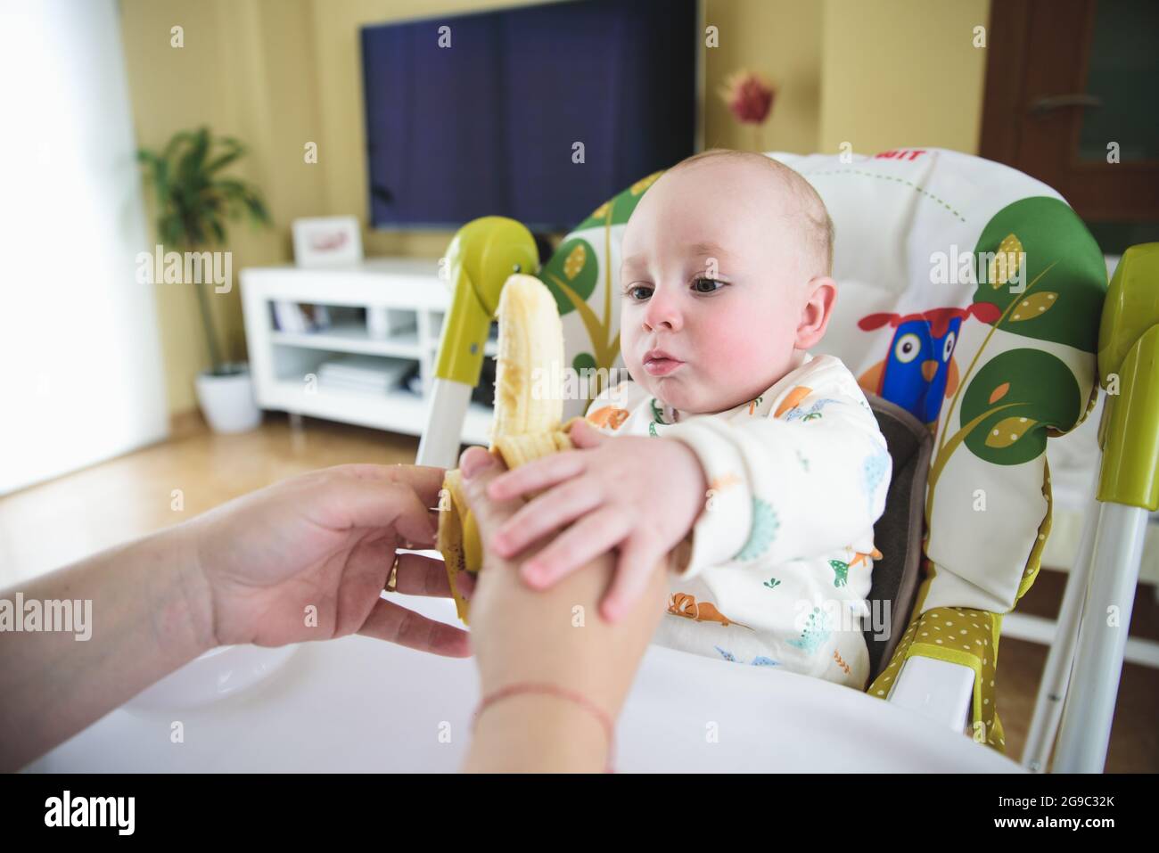 woman giving banana to her baby Stock Photo - Alamy