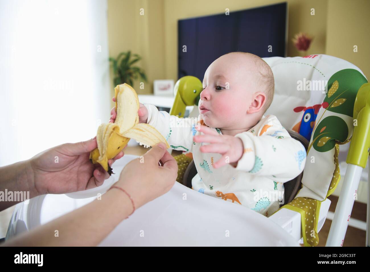 woman giving banana to her baby Stock Photo - Alamy