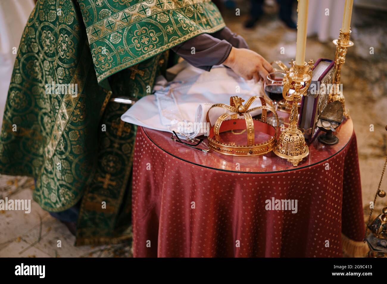 Priest stands in front of the wedding table with crowns, candles and a ...