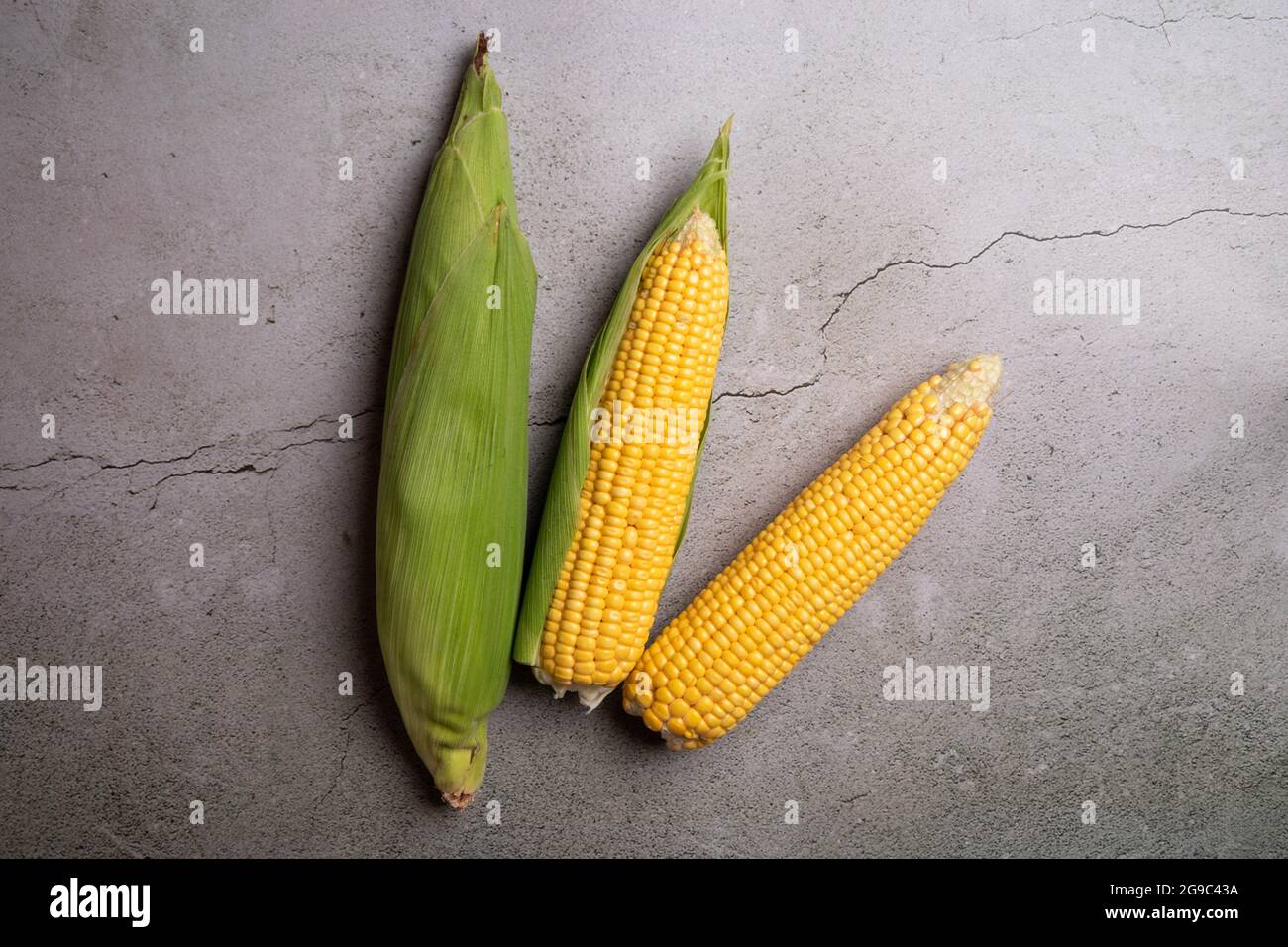 Fresh corn cobs on flat concrete background Stock Photo - Alamy