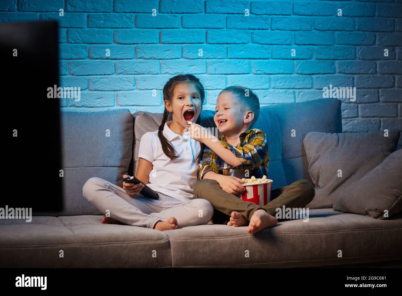 two children with remote control watching TV Stock Photo - Alamy