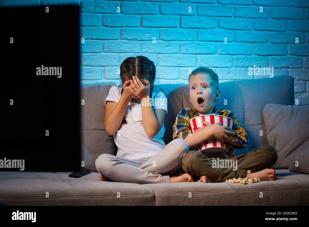 two children with remote control watching TV Stock Photo - Alamy