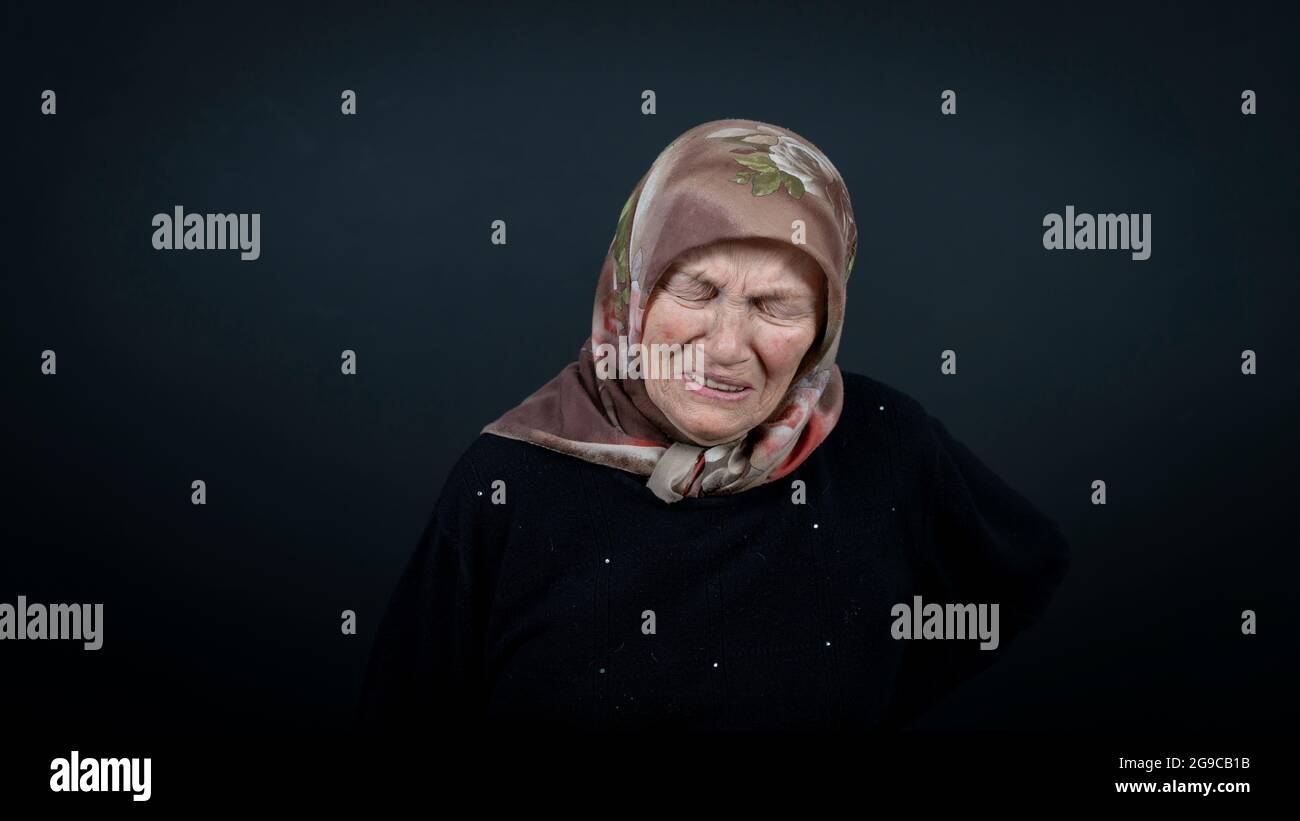 Portrait of a Turkish senior muslim woman with black background. She is ...