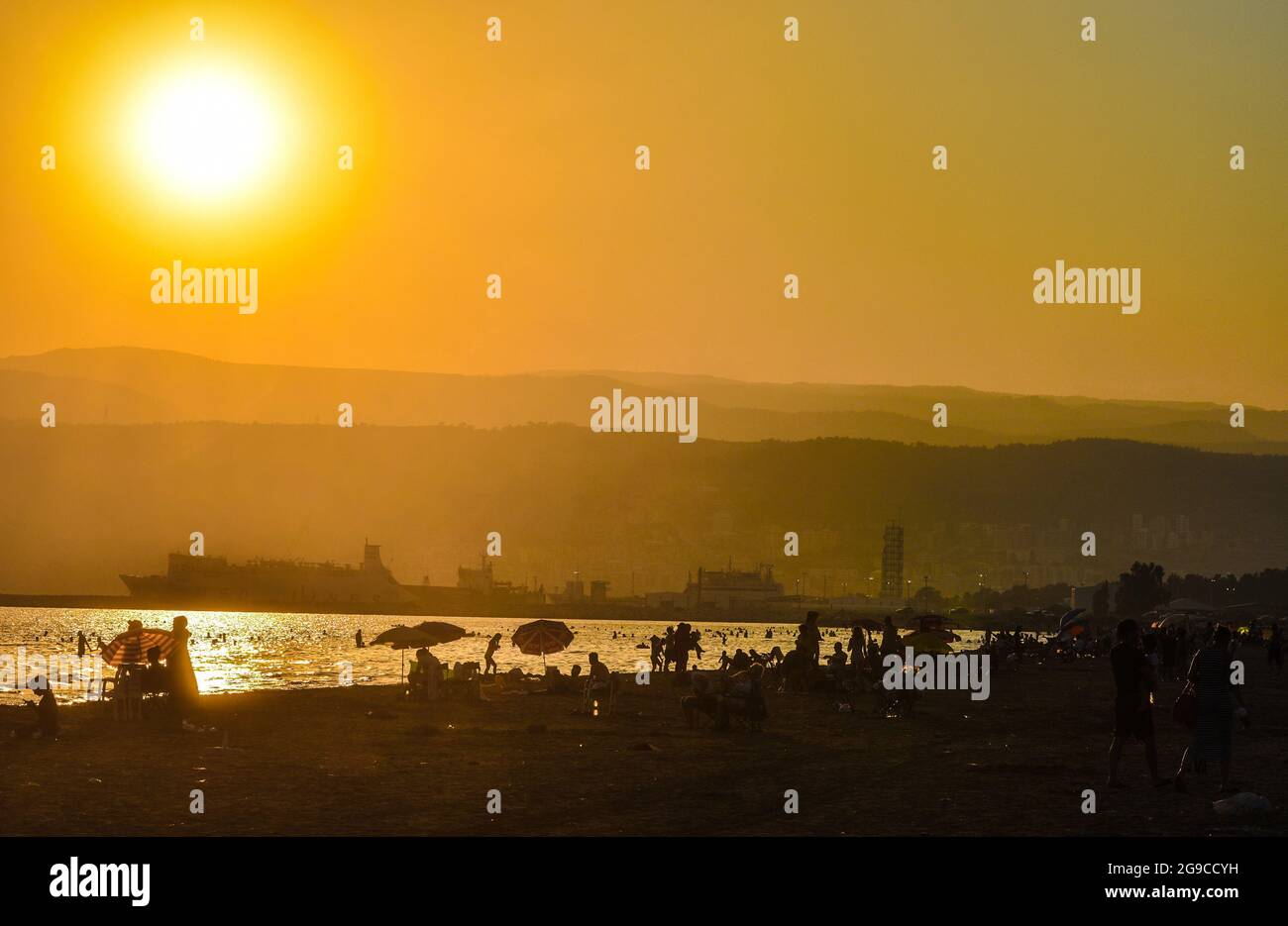 People flock to a beach during sunset in the coastal town of Tasucu in ...
