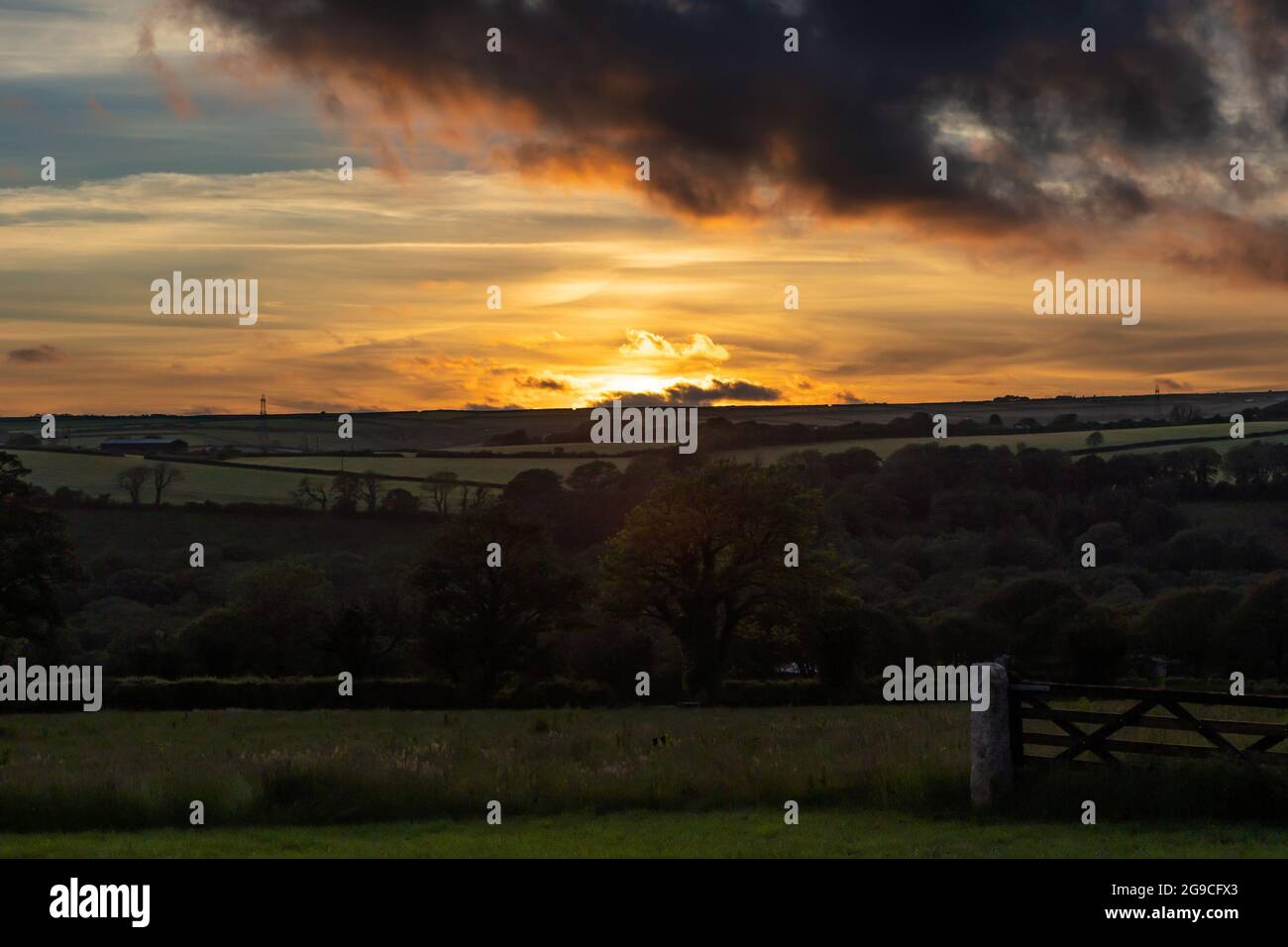 A Beautiful scenery of cloudy orange dark sky at sunset over a green ...