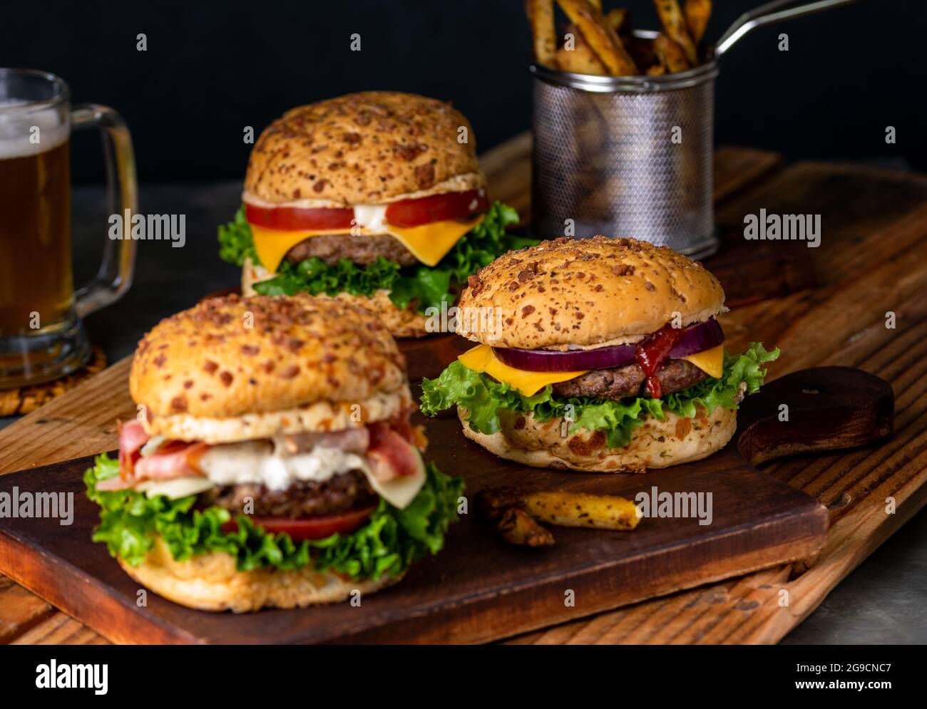 A closeup of three delicious hamburgers served on a wooden board with ...