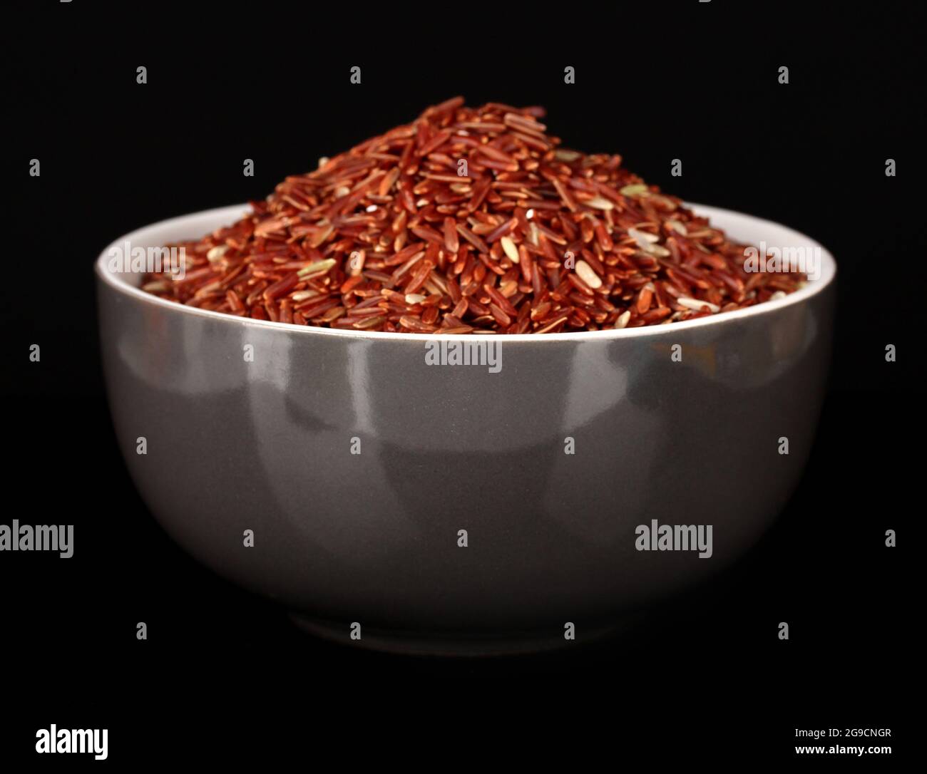 Red rice in gray bowl isolated on black Stock Photo - Alamy