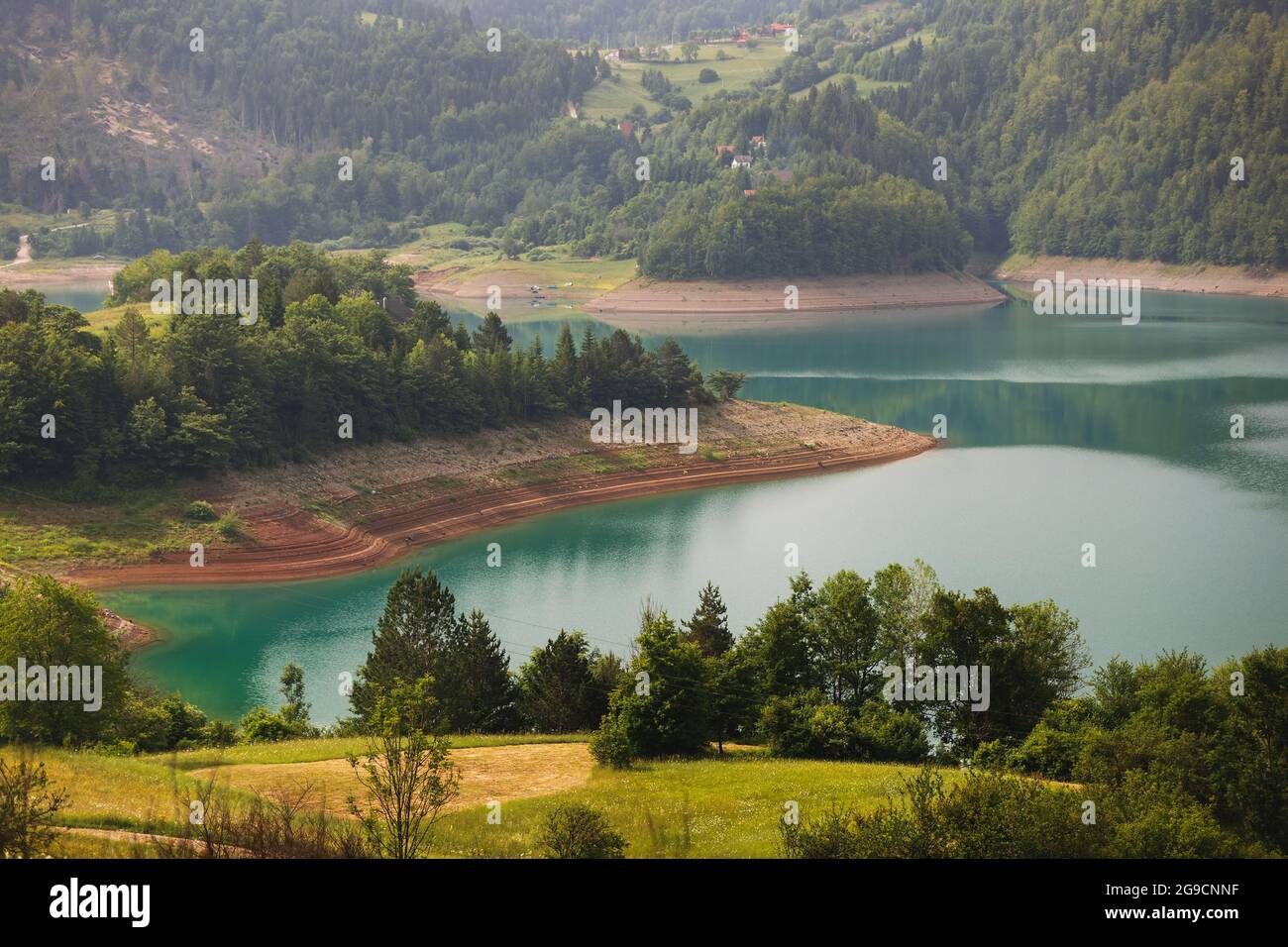 Beautiful view of mountain lake and fields in misty summer morning ...