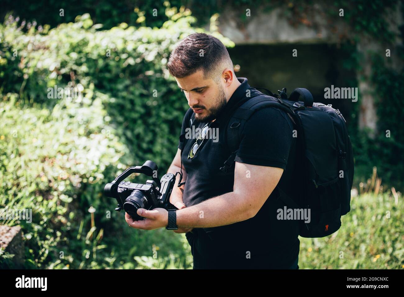 A shot of a man in a black shirt holding camera on a gimbal in a ...