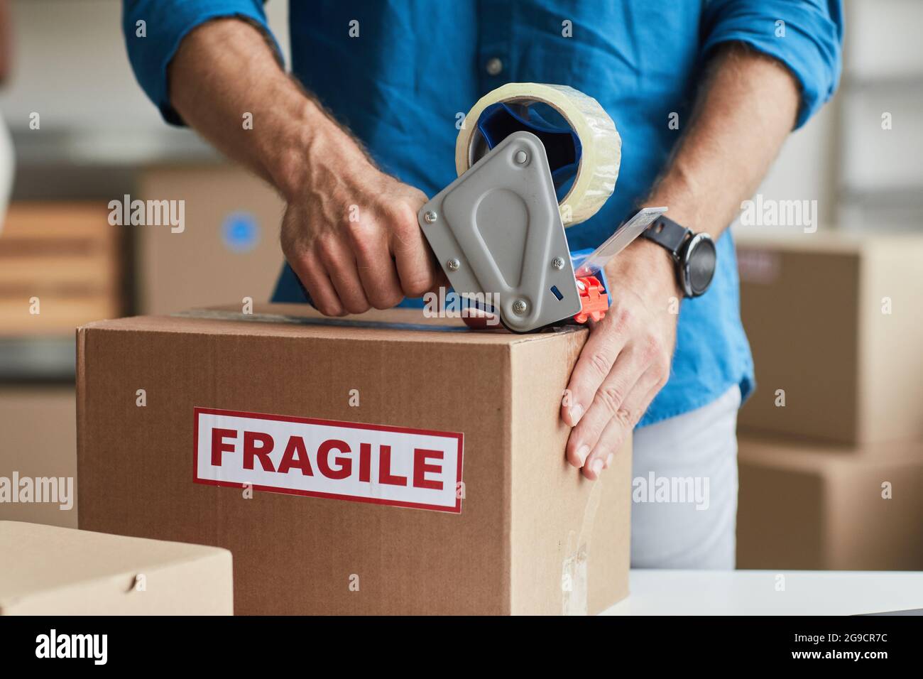Close up of young man packing boxes with Fragile sticker at warehouse ...