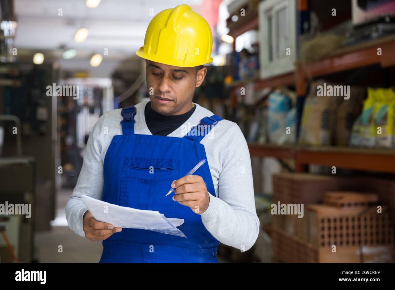 Focused salesman checking goods on shelves of construction hypermarket ...