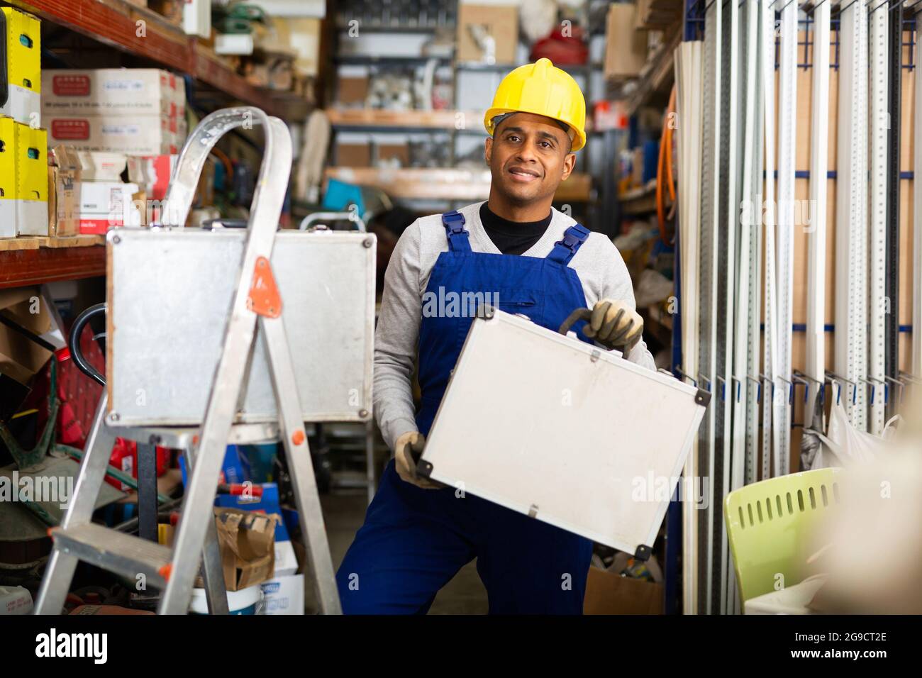 Smiling latin american foreman standing with tool case in store Stock ...