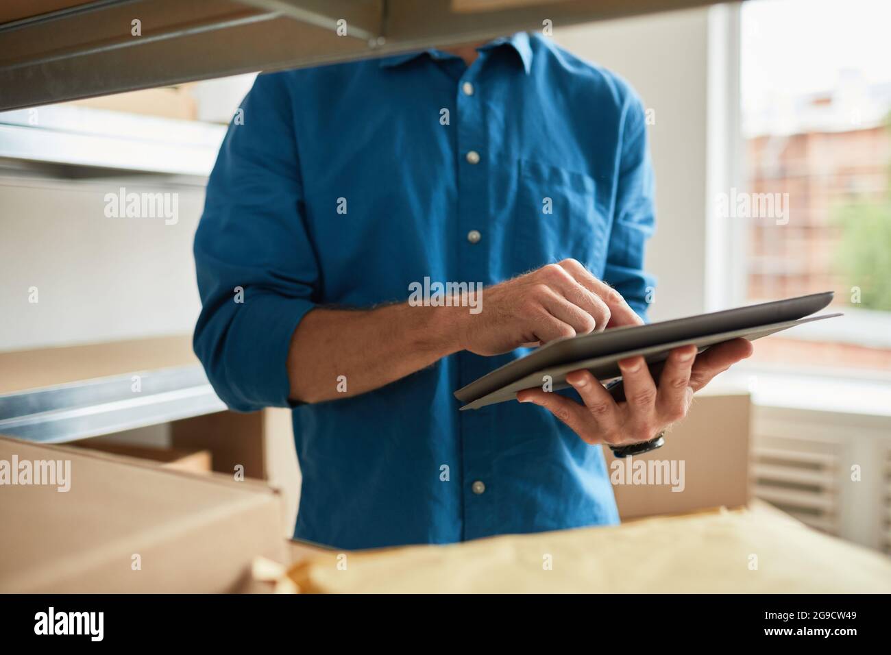 Cropped shot of young man using digital tablet in warehouse while doing ...