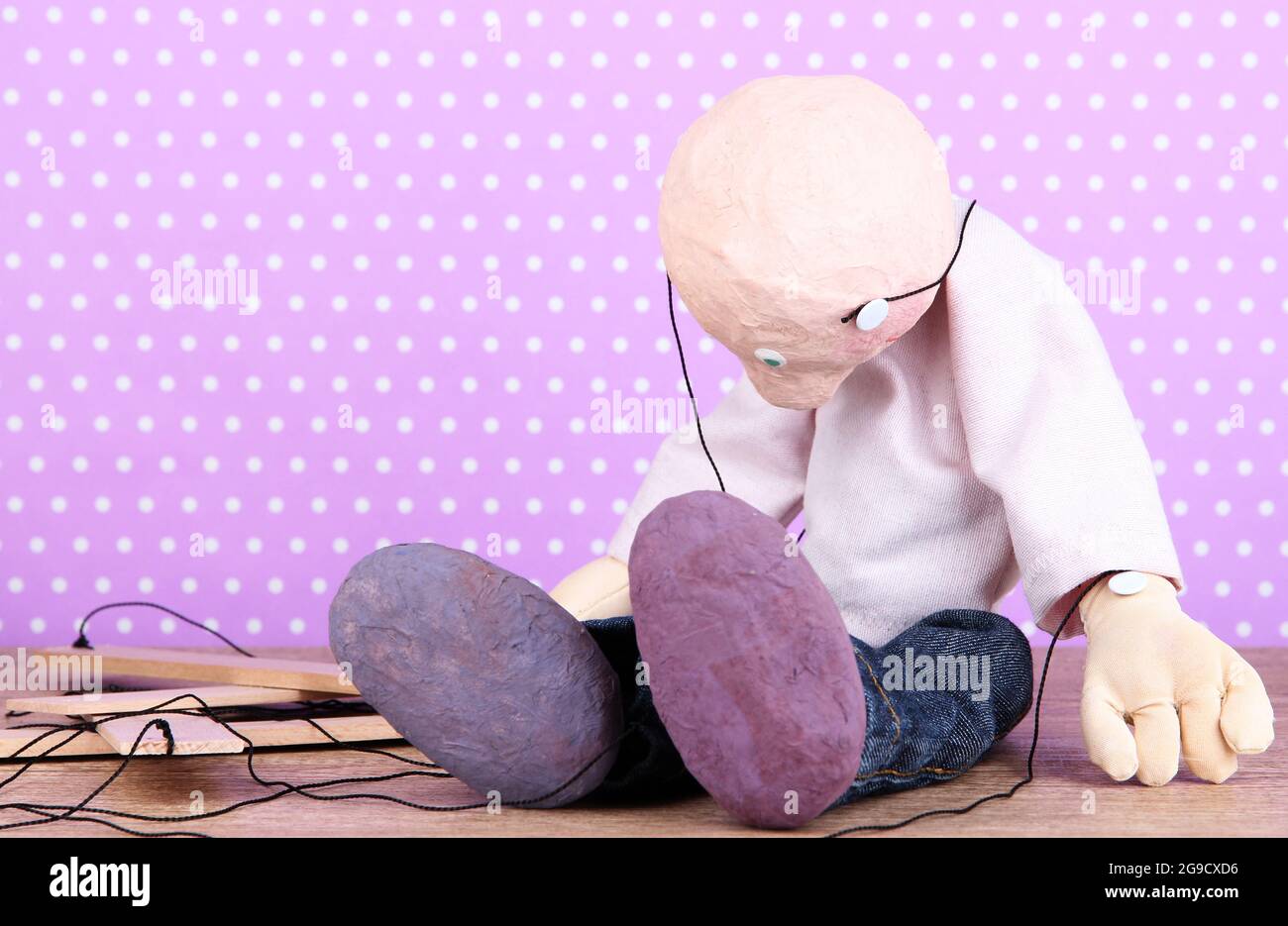 Wooden puppet sitting on polka dot background Stock Photo - Alamy