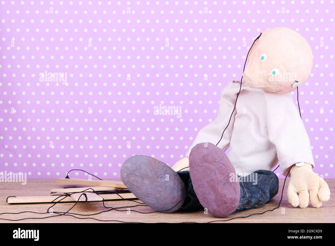 Wooden puppet sitting on polka dot background Stock Photo - Alamy