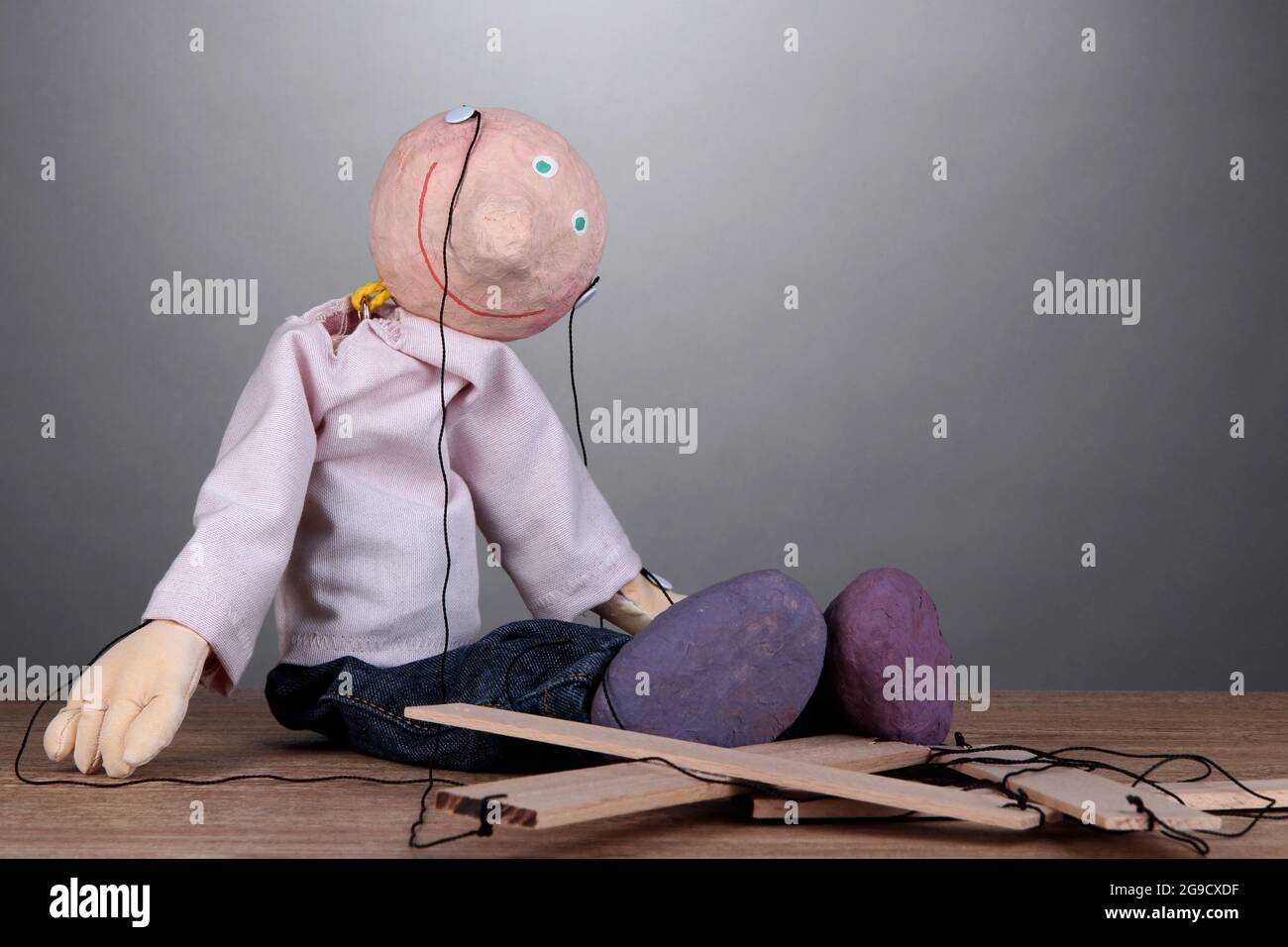 Wooden puppet sitting on grey background Stock Photo - Alamy