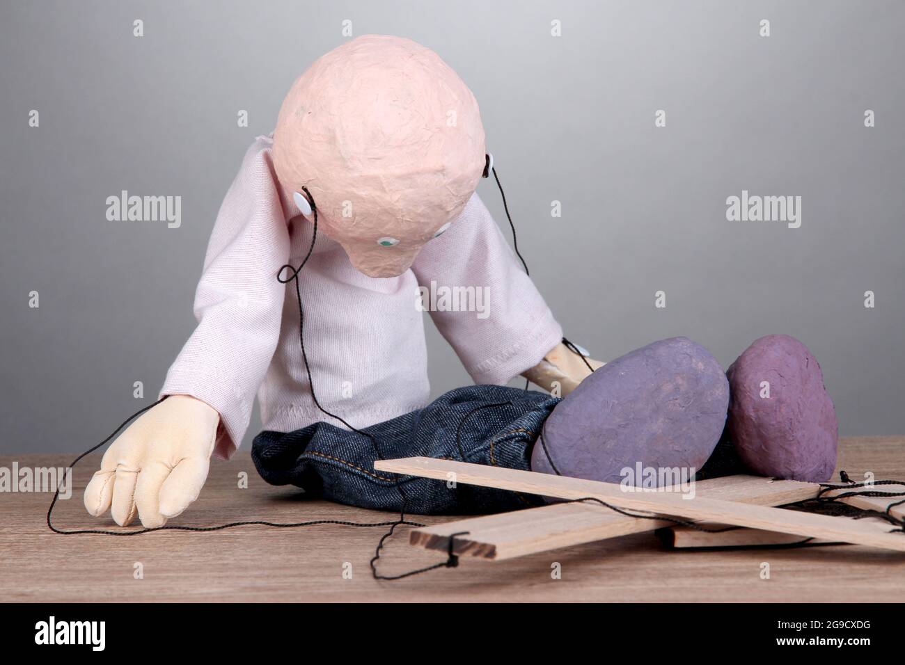 Wooden puppet sitting on grey background Stock Photo - Alamy