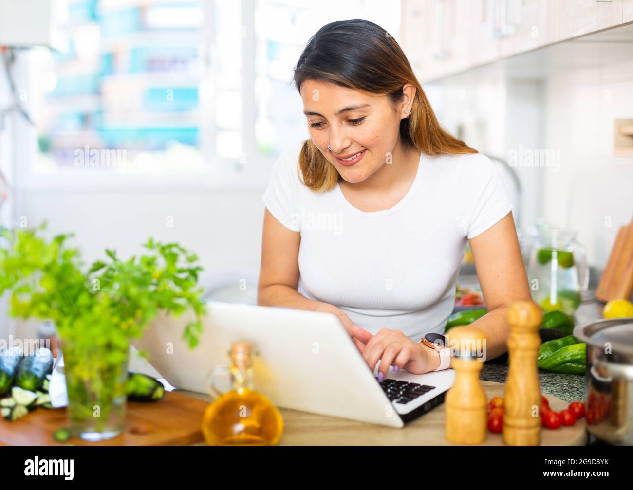 Woman cooking soup and watching movie at laptop Stock Photo - Alamy